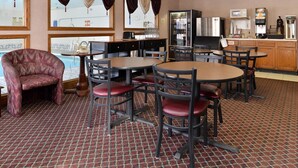 Restaurante com vista para a piscina, mesas, cadeiras, frigorífico e máquina de café.