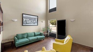 Uma sala de estar com um sofá verde, uma poltrona amarela e uma televisão de tela plana na parede.