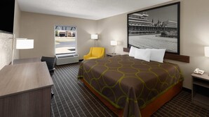 Quarto de hotel com uma cama grande, uma escrivaninha, uma cadeira e uma janela com vista para a rua.
