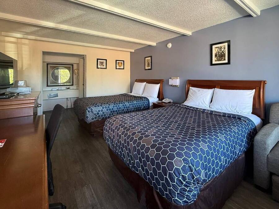 Quarto de hotel com duas camas, uma escrivaninha e uma cadeira.