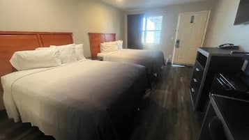 Quarto de hotel com duas camas, uma escrivaninha, um armário e uma janela.
