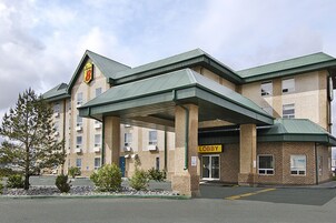 Um hotel com entrada para o saguão, vários andares e um telhado verde.