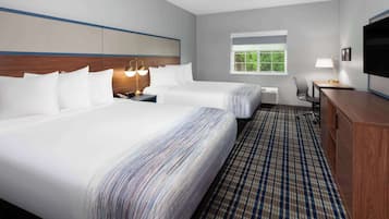 Quarto de hotel com duas camas, uma janela grande, televisão de tela plana e escrivaninha com luminária.