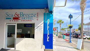 Exterior do Hotel Sea & Breeze Tybee Island, com um aviso de 'VACANCY' visível e um posto de estacionamento particular.