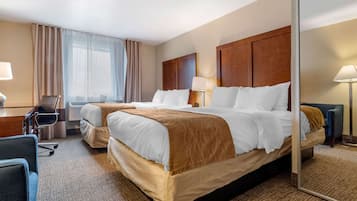 Quarto de hotel com duas camas, uma escrivaninha, uma cadeira e um espelho grande.