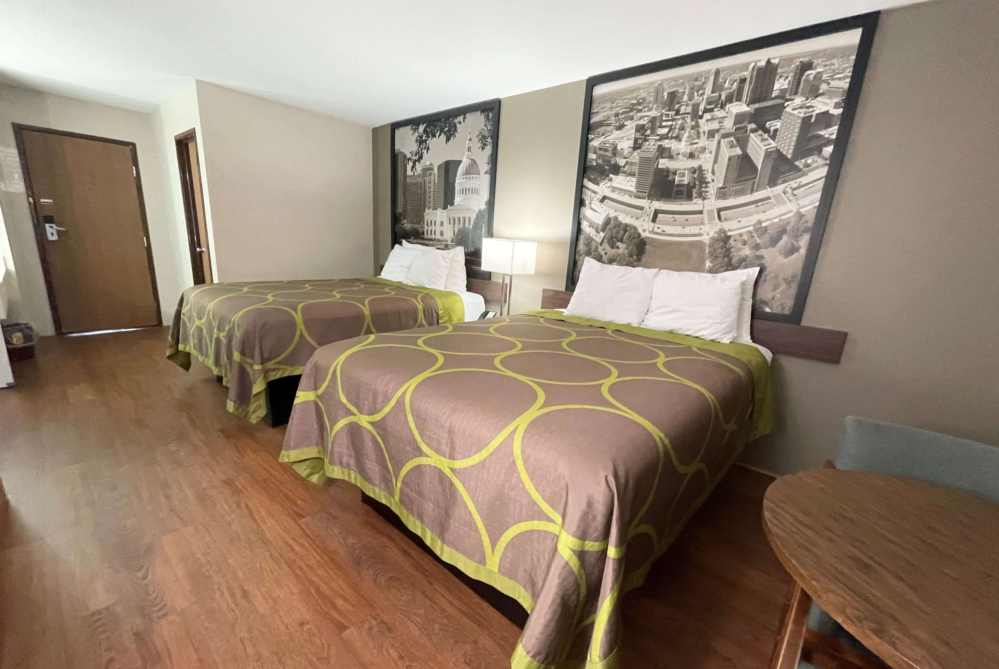 Quarto de hotel com duas camas, piso de madeira e arte urbana na parede.