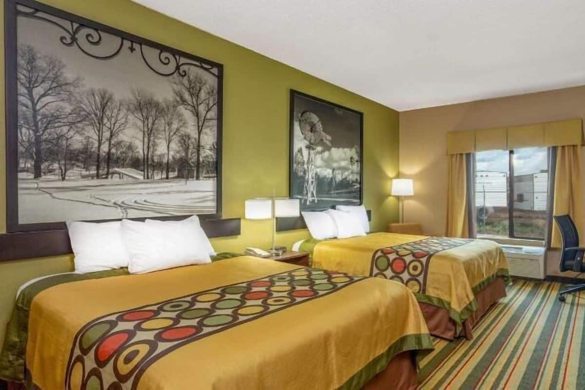 Quarto de hotel com duas camas, televisão, escrivaninha e janela com vista.