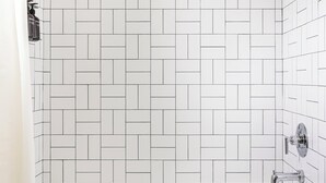 Um banheiro moderno com parede de azulejos brancos, banheira e chuveiro.