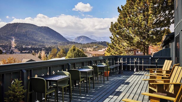 Um terraço com área de estar ao ar livre, com vista para uma paisagem montanhosa.