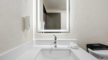 Uma casa de banho moderna com uma sanita branca, um espelho e uma pia.