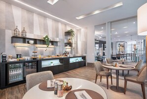 Um lobby moderno de hotel com área de bar, assentos e vista para a sala de jantar.