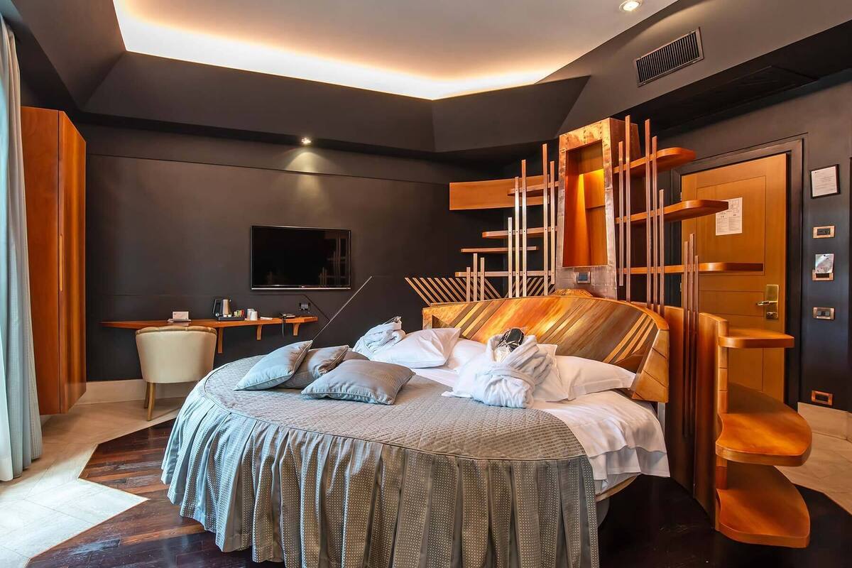 Quarto de hotel moderno com uma cama grande, uma escrivaninha e uma televisão.