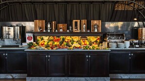 Disposição de buffet com diversos alimentos e máquinas de café.