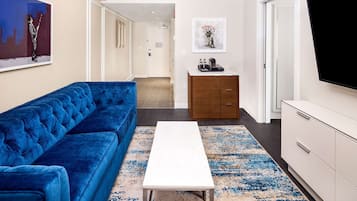 Uma sala de estar moderna com um sofá azul, uma mesa de centro branca e uma televisão na parede.