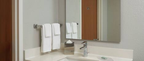 Um banheiro moderno com uma pia branca, um espelho e duas toalhas penduradas em um porta-toalhas.