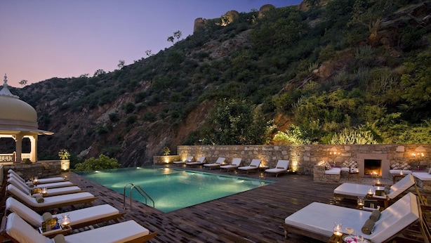Uma área à beira da piscina com espreguiçadeiras e um muro de pedra.