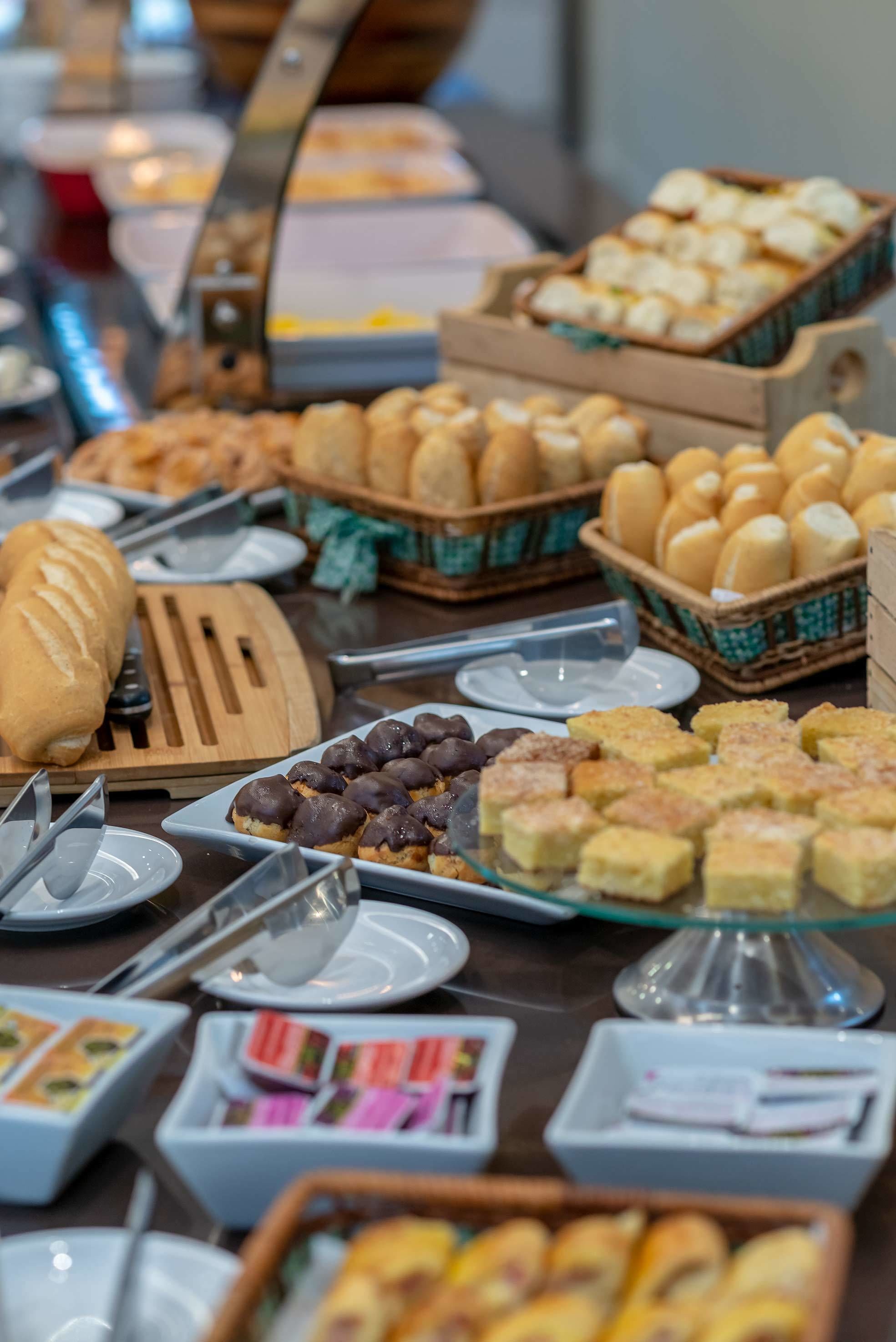 Um buffet com diversos pães e doces.