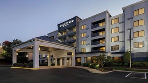 Um hotel Courtyard by Marriott com entrada coberta, várias varandas e estacionamento.