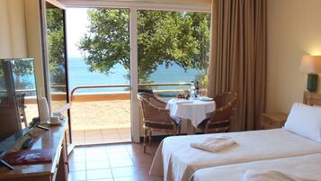 Quarto de hotel com varanda com vista para uma praia e o mar.