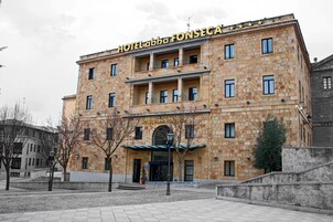 Um hotel com vários andares, fachada de pedra, varandas e entrada central.