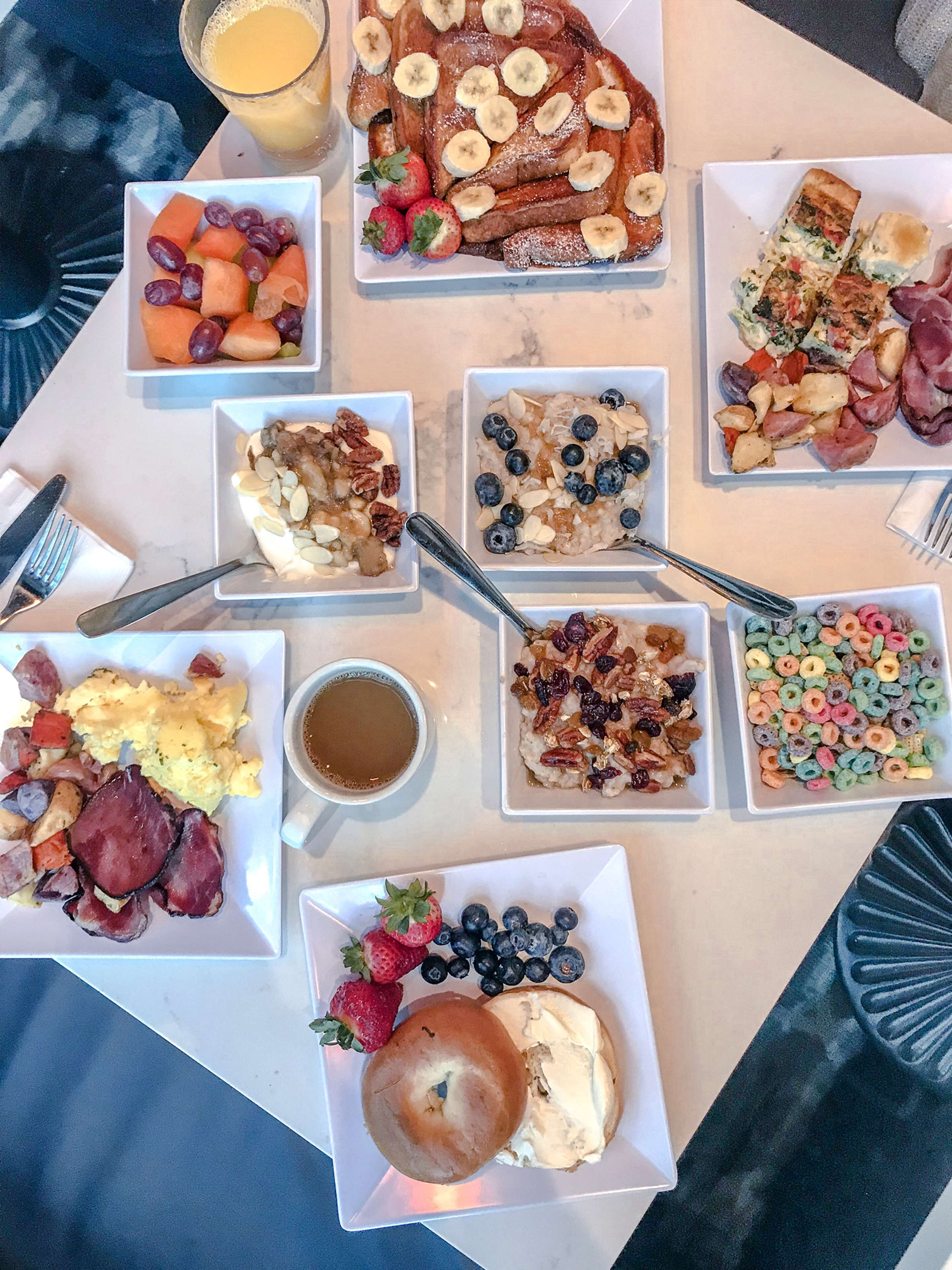 Um buffet de café da manhã com diversos pratos, incluindo panquecas, cereais, ovos e frutas.
