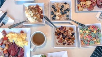 Um buffet de café da manhã com diversos pratos, incluindo panquecas, cereais, ovos e frutas.
