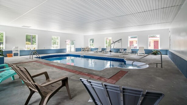 Uma área de piscina com espreguiçadeiras e um solário, cercada por janelas e portas.
