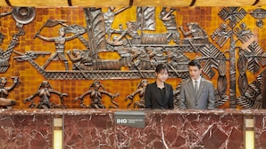 Uma mesa de recepção com uma escultura de metal representando guerreiros e uma placa com a inscrição "IHG Rewards Club".