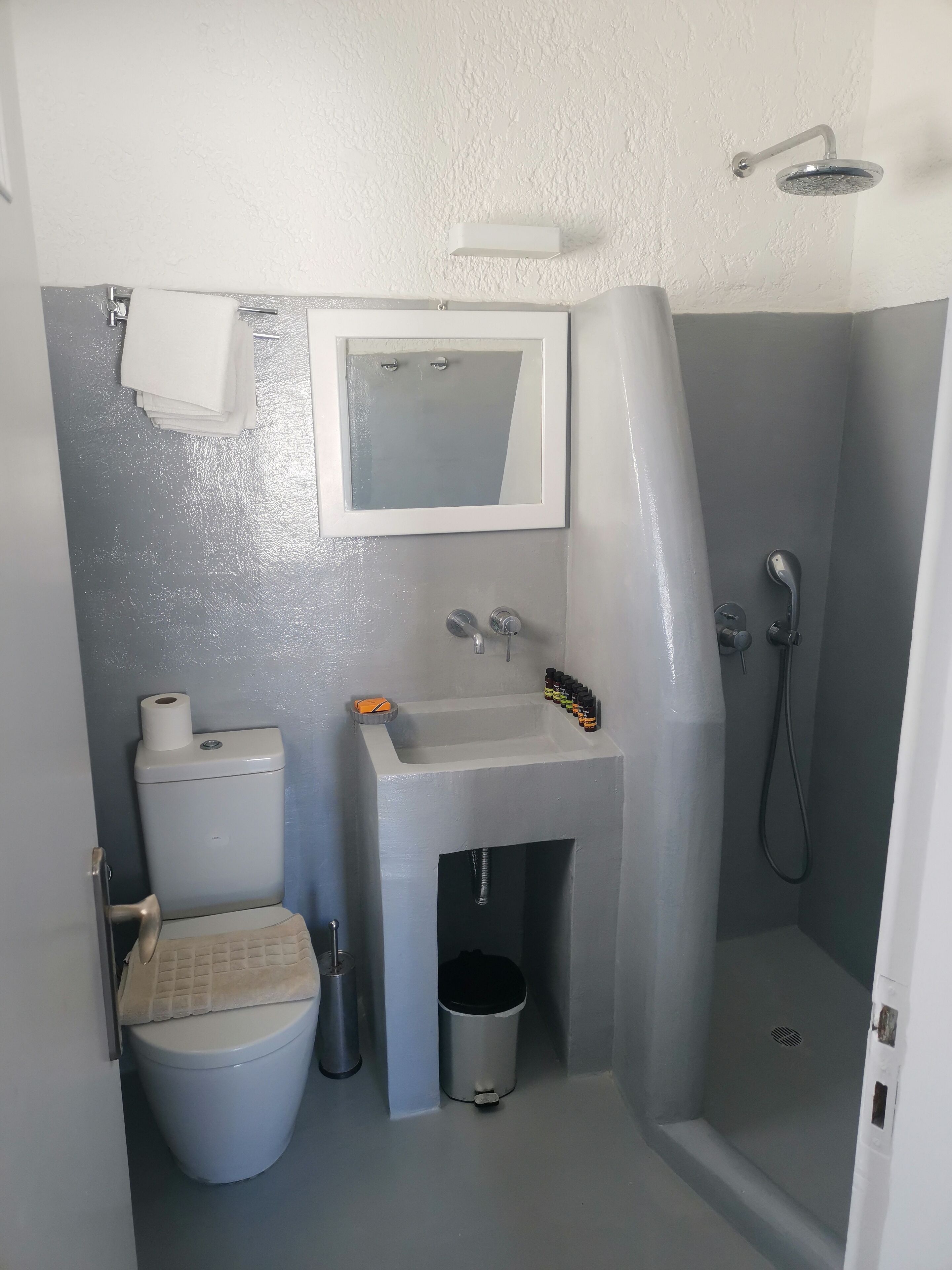 Casa de banho compacta com sanita, lavatório e chuveiro.
