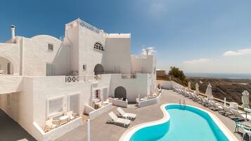 Um edifício branco com piscina, espreguiçadeiras e vista para a paisagem.