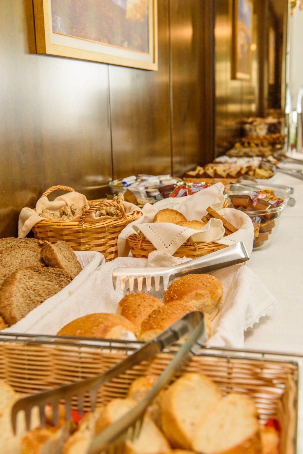 Uma mesa de buffet com diversos alimentos, incluindo pão, doces e uma seleção de queijos.