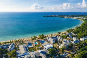 Um resort costeiro com vários edifícios, uma praia e uma vista clara do oceano.