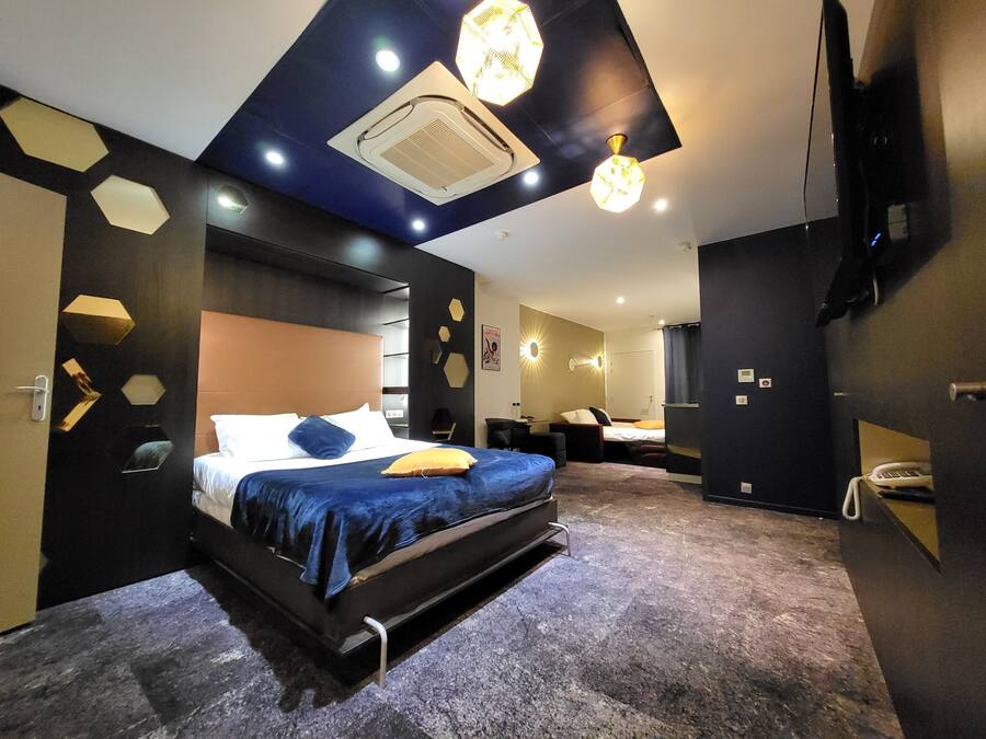 Quarto moderno com cama, escrivaninha e área de chuveiro.