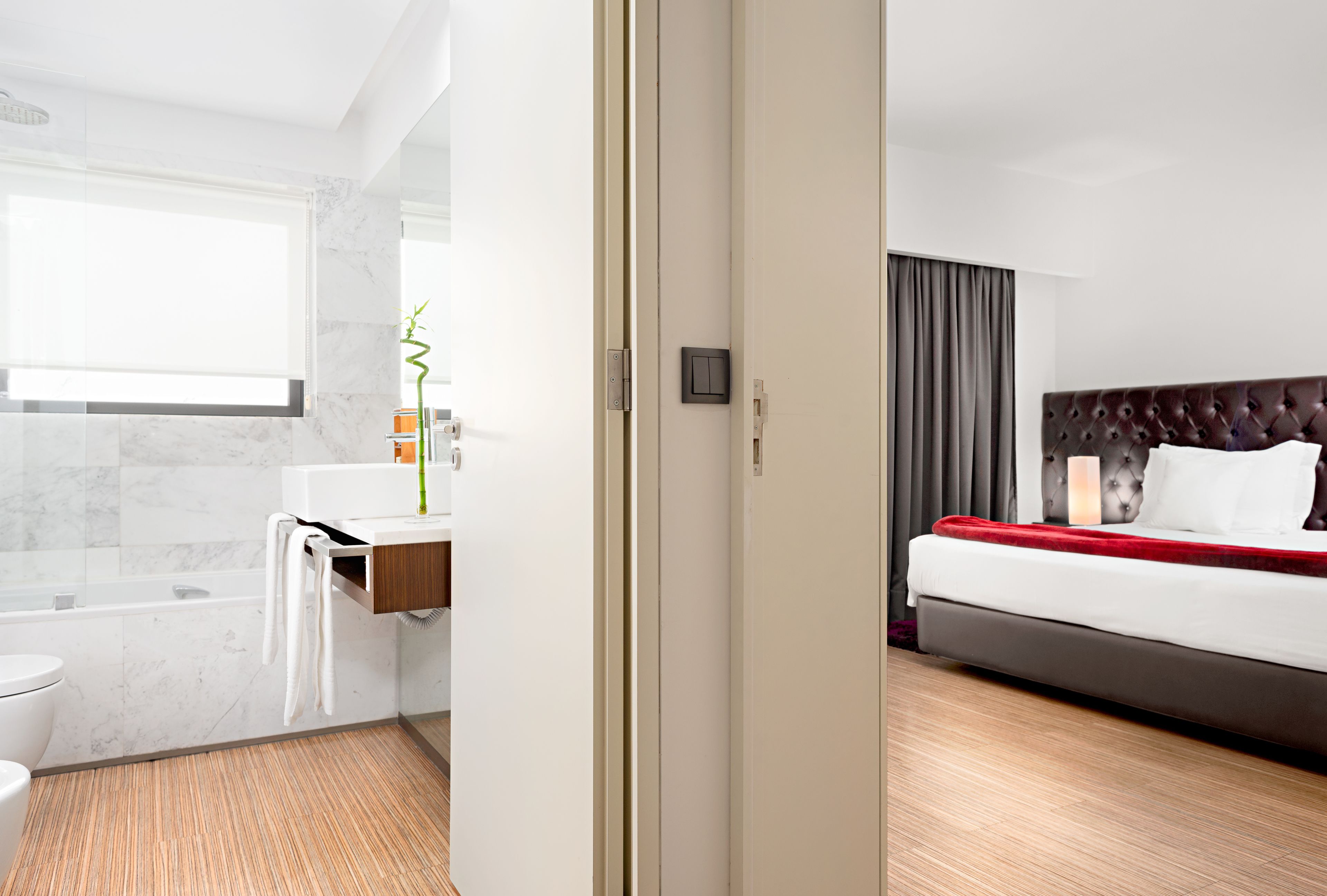 Quarto de hotel moderno com banheiro, cama e piso de madeira.