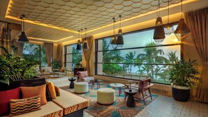 Um hall de hotel moderno com uma grande janela, assentos confortáveis e iluminação decorativa.