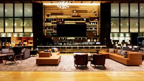 Espaço lounge moderno com bar, assentos e uma grande parede de exibição.