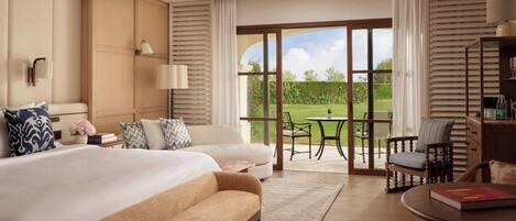 Quarto de hotel com uma cama grande, um sofá, uma mesa de jantar e vista para o exterior.
