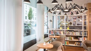 Uma biblioteca moderna com várias estantes, mesas de leitura e luminárias pendentes pretas.