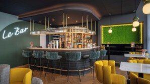 Uma área de bar com balcão curvo, banquetas e um letreiro de neon.