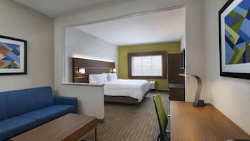 Quarto de hotel com cama, escrivaninha, cadeira, sofá e janela.