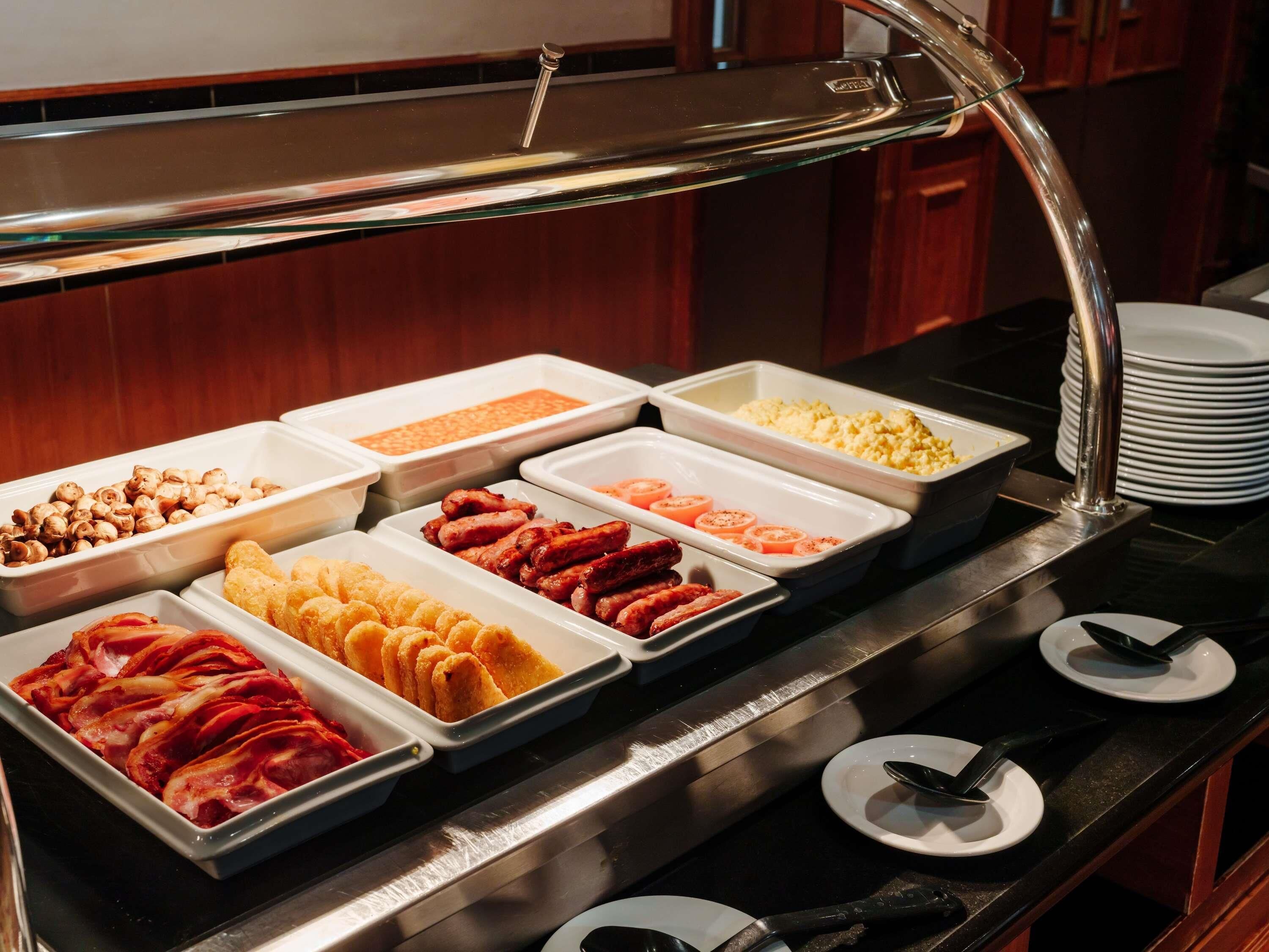 Buffet com diversos alimentos e um dispensador de água.