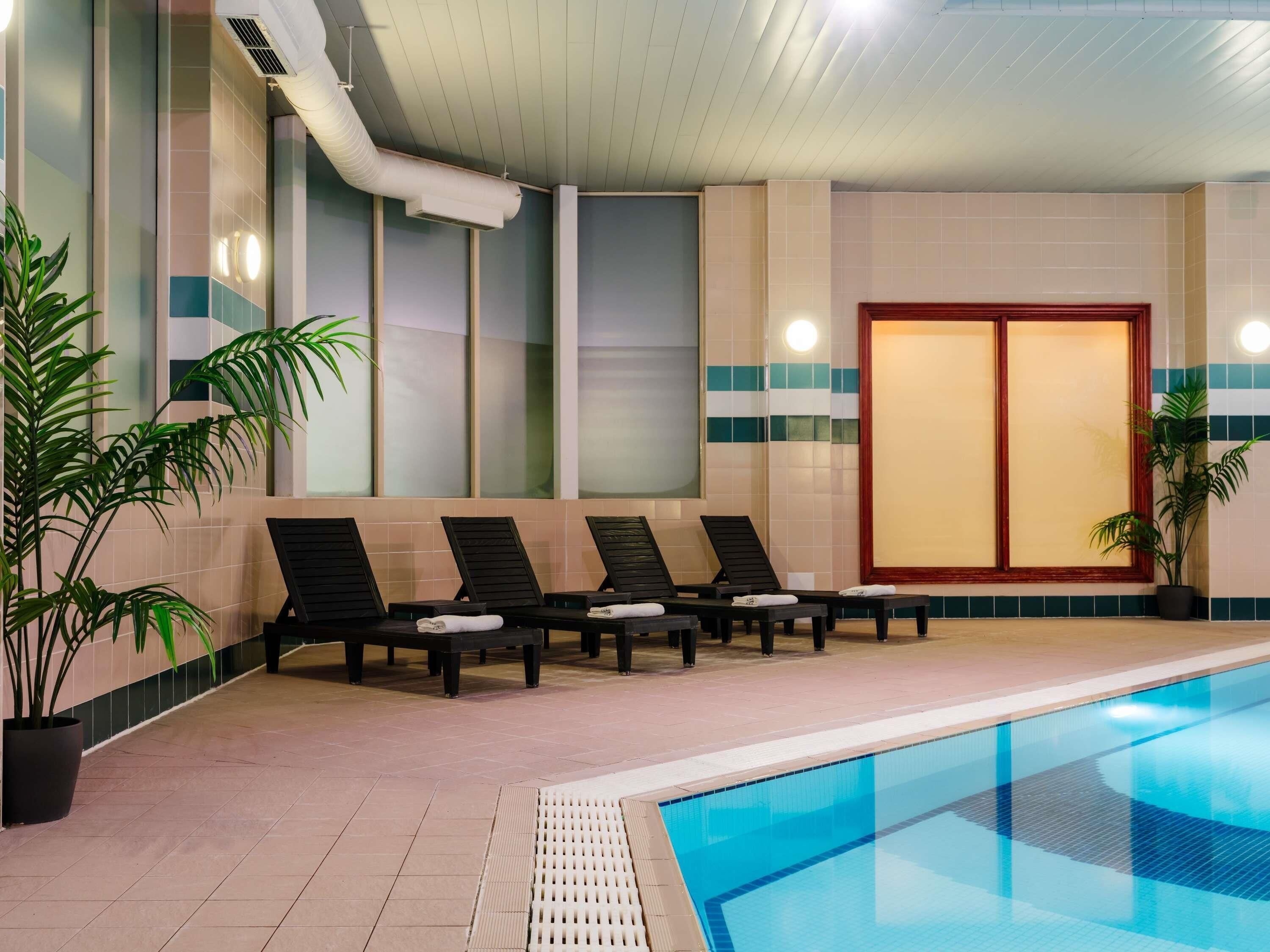 Área de piscina com espreguiçadeiras e plantas em vasos.