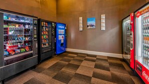 Um corredor com máquinas de venda automática, incluindo um bebedouro de água DASANI e um refrigerador de Coca-Cola.