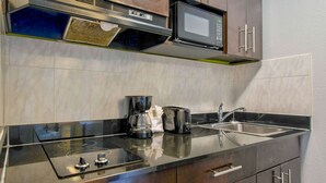 Uma cozinha moderna com fogão de aço inoxidável, micro-ondas e máquina de café.