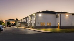 Hotel de vários andares com entrada coberta, área de estacionamento e fachada bem iluminada.