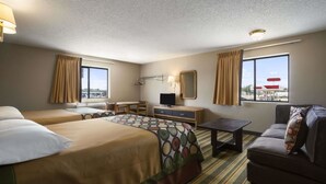 Quarto de hotel com duas camas, uma mesa, televisão e um sofá.