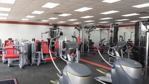 Uma academia com diversos equipamentos de ginástica, esteiras e aparelhos de musculação.