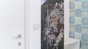 Casa de banho com parede revestida em azulejos com vista urbana e um armário branco com porta.
