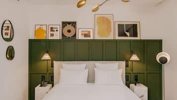 Quarto de hotel bem arrumado com cabeceira verde, uma cama grande, duas mesas de cabeceira com luminárias e um lustre.