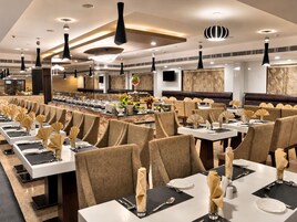Um restaurante com várias mesas, cadeiras e iluminação pendente moderna.